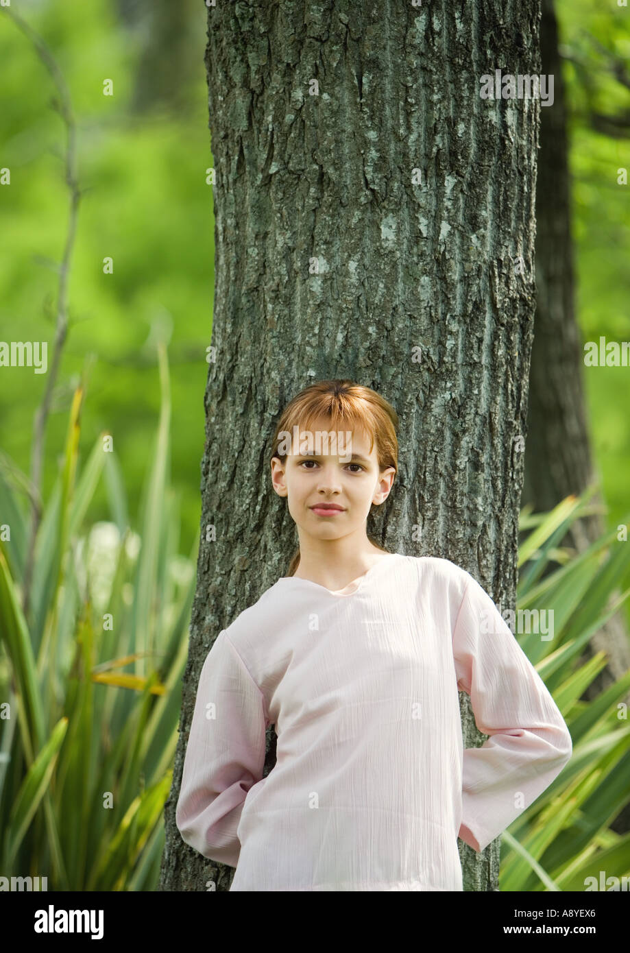 Girl leaning against tree trunk Stock Photo - Alamy