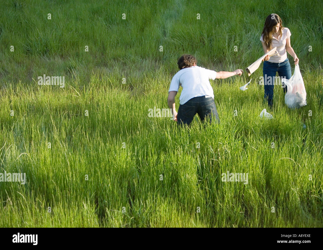 Young couple picking up litter in field Stock Photo - Alamy