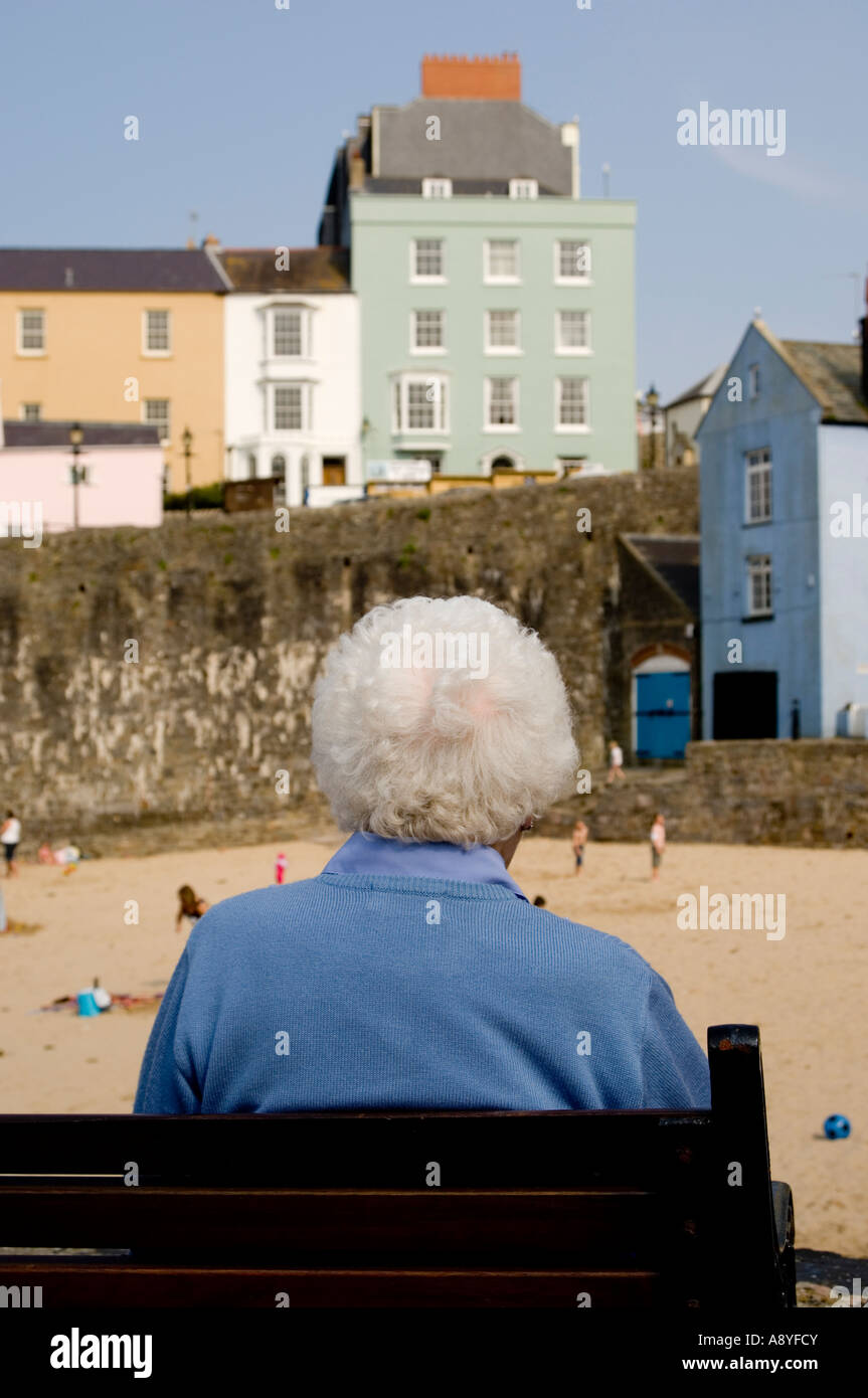 rear view from behind of an old woman lady grey hair sitting alone on ...