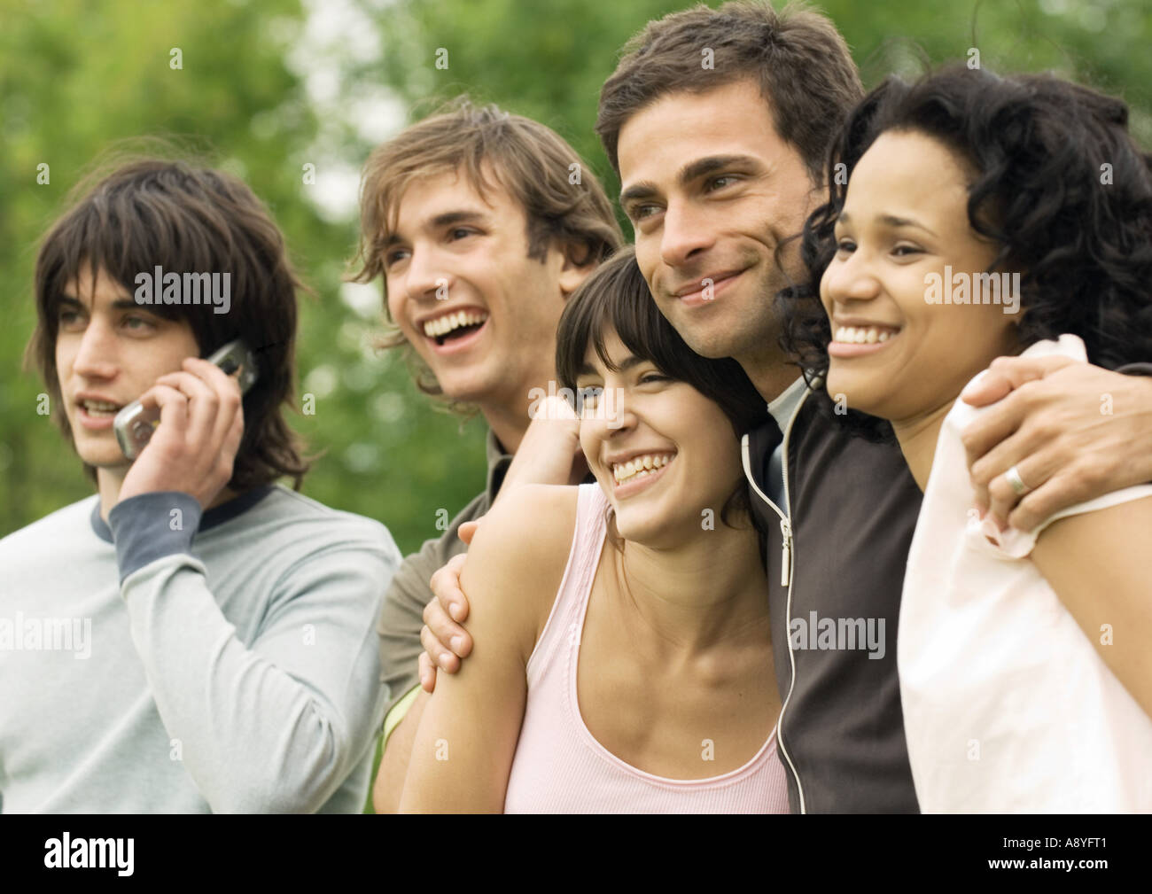 Group of young friends smiling, one using cell phone Stock Photo - Alamy
