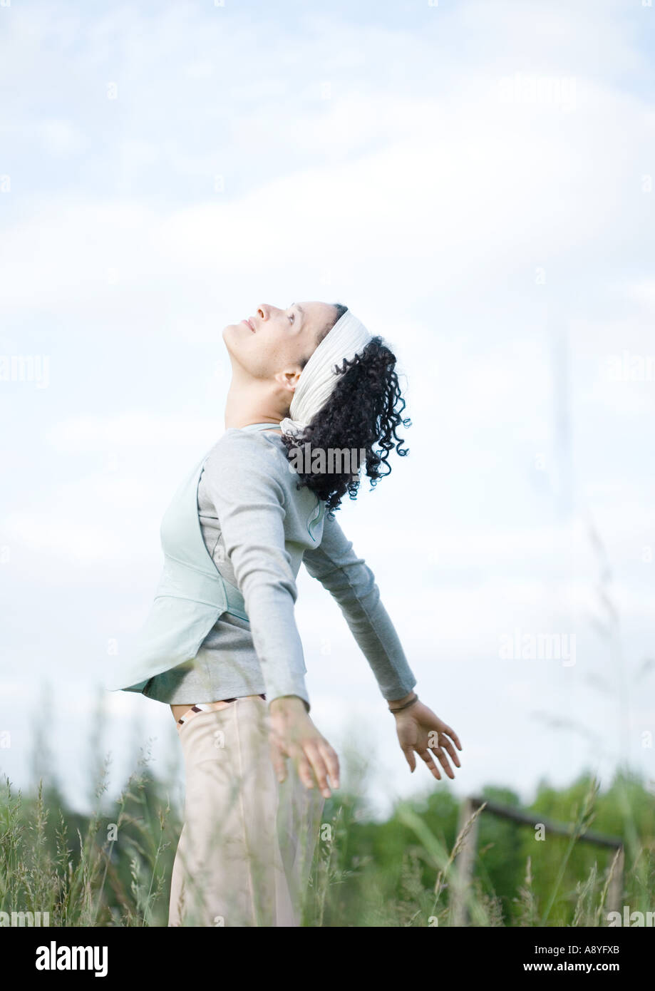 Young woman standing in grass with head and arms thrown back Stock ...