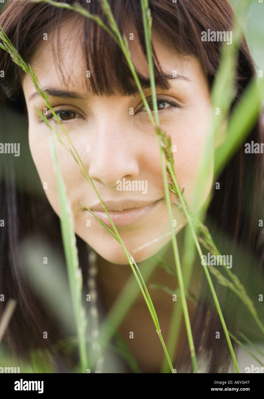 Woman's face seen through blades of grass Stock Photo - Alamy