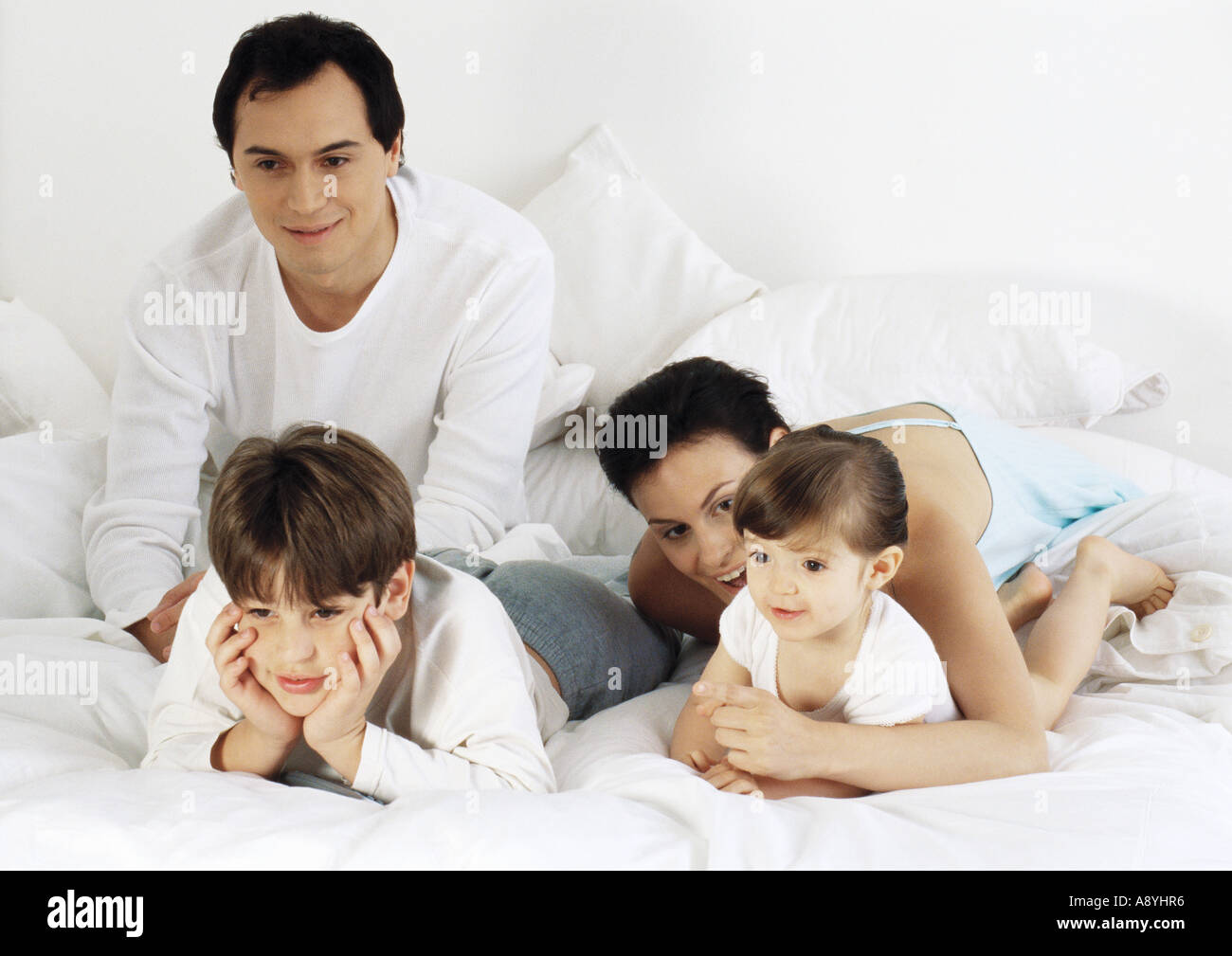 Family lying on bed together Stock Photo - Alamy