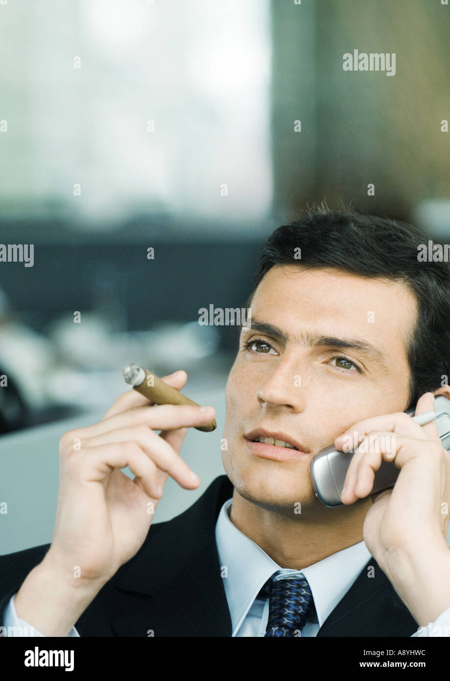 Businessman using cell phone and smoking cigar Stock Photo - Alamy