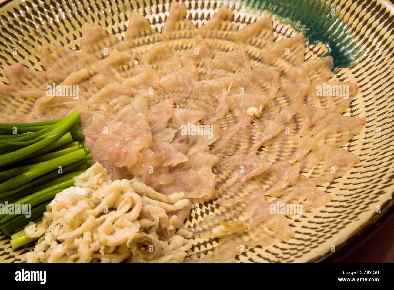Plate of freshly prepared fugu blowfish sashimi with spring onions ...
