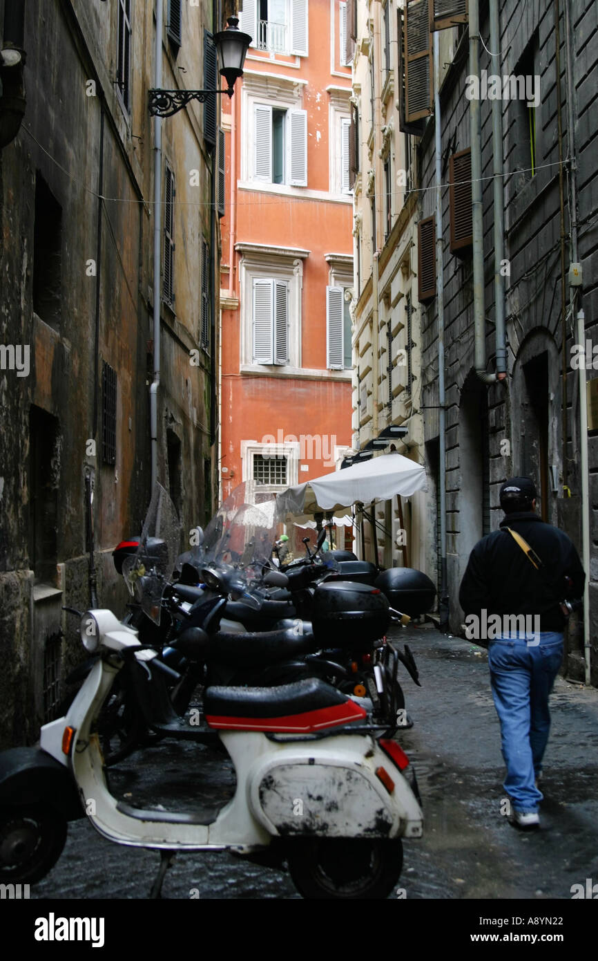Man on side street in Italy lined with scooters Stock Photo - Alamy