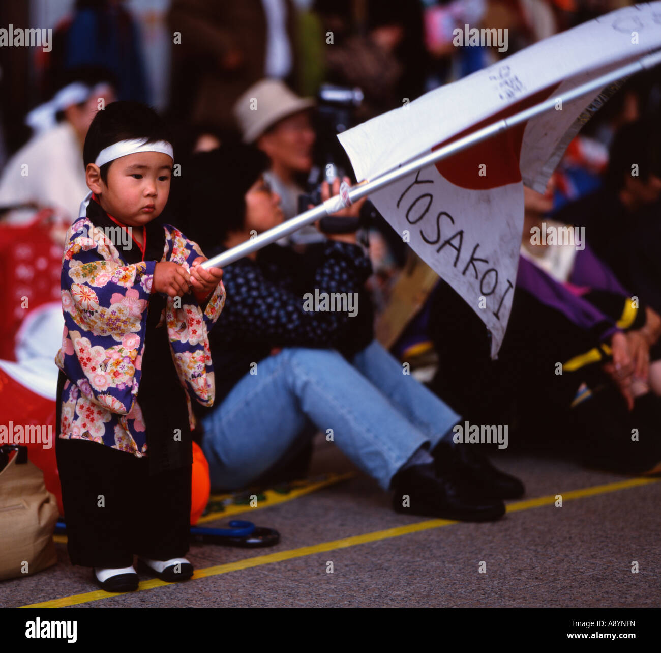 Young child waving the Japanese flag while taking part in the Yosakoi ...