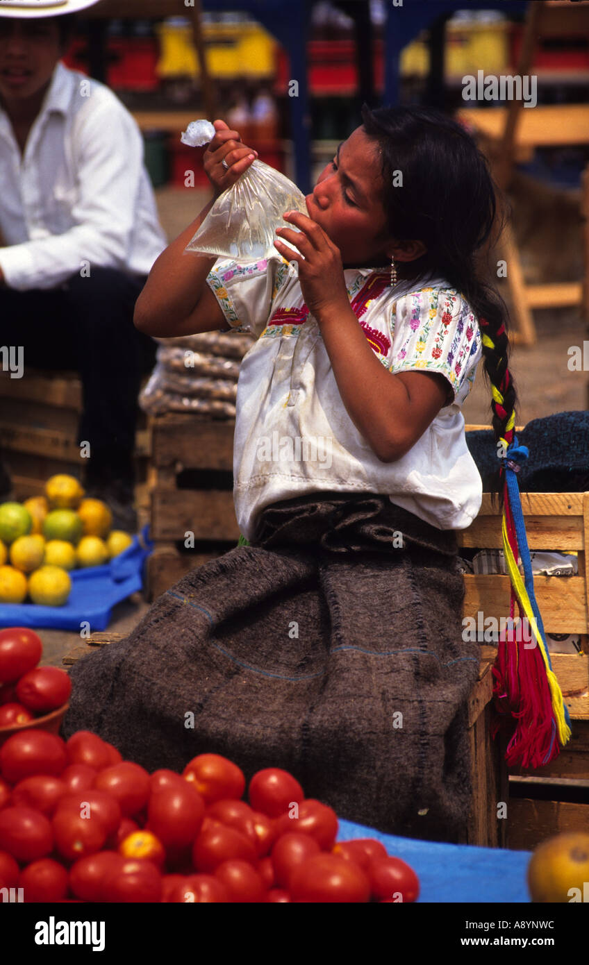 A CHAMULAN MAYAN INDIAN WOMAN DRINKS FROM A PLASTIC BAG AT A MARKET IN ...