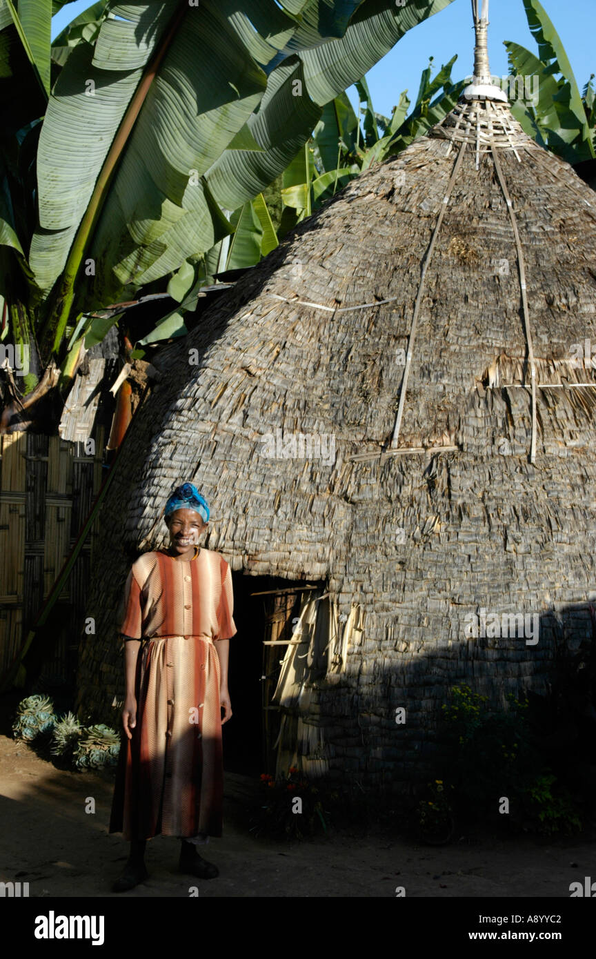 Woman of the Dorze people standing in front of her typical beehouse ...