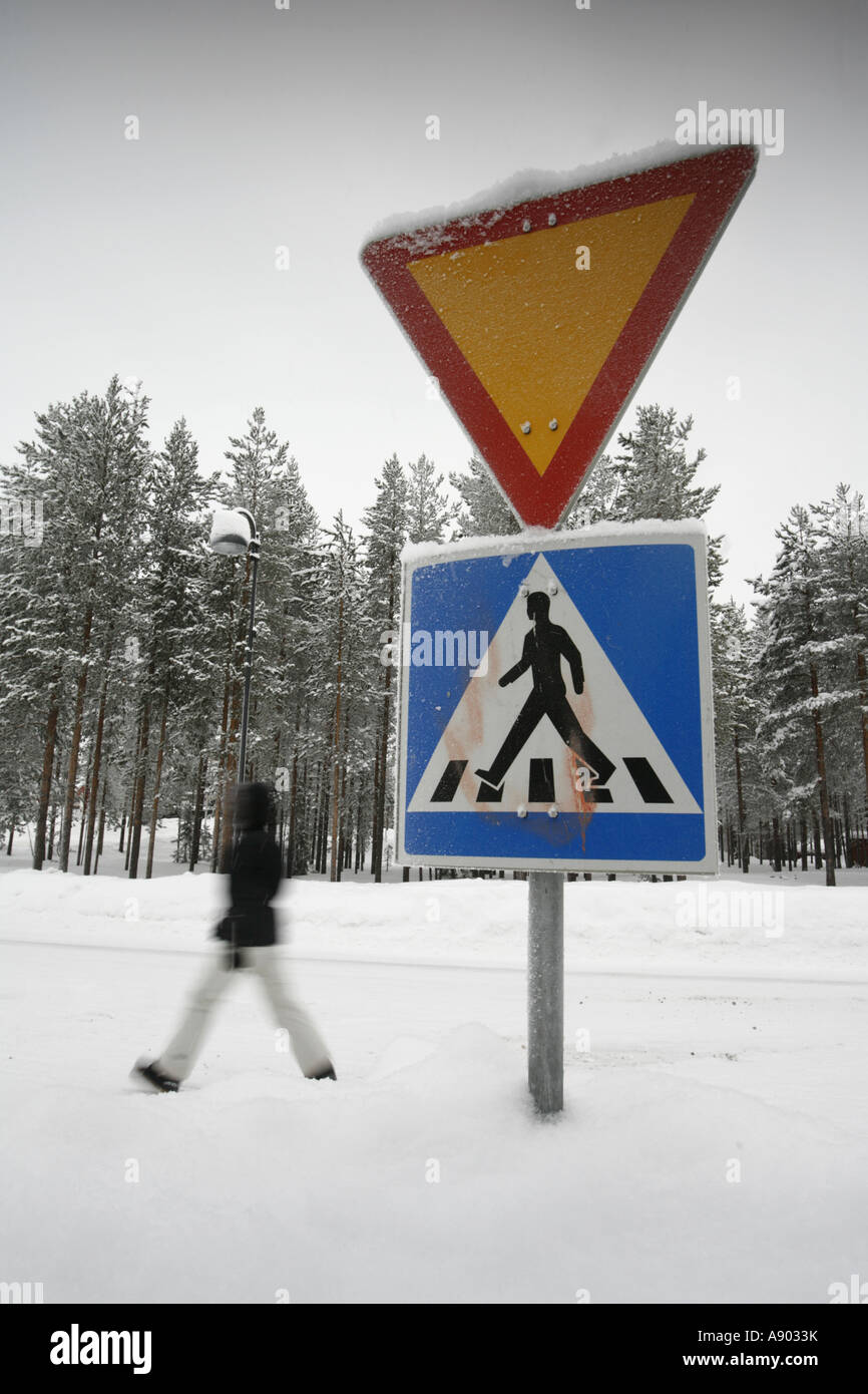 Female tourist crossing a snow covered road near a road sign Stock ...