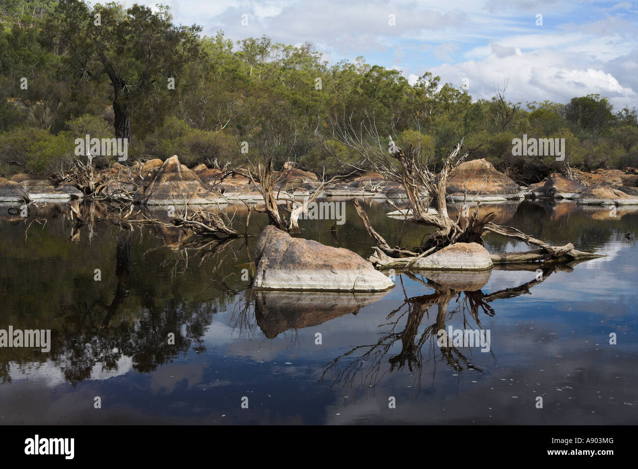 boulders and dead trees create reflections and patterns in a Billabong ...