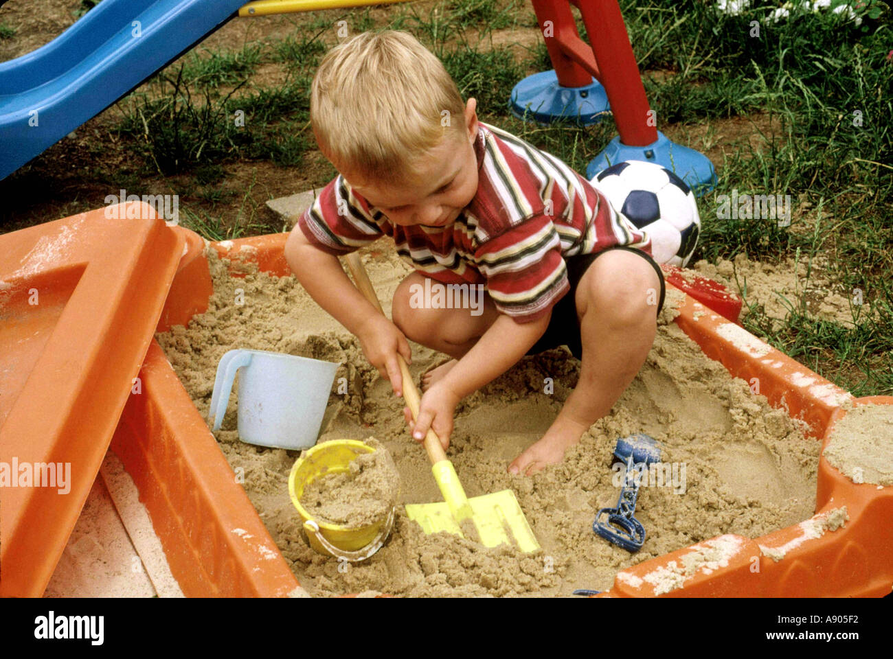 Boy playing with bucket and spade in the sand hi-res stock photography ...