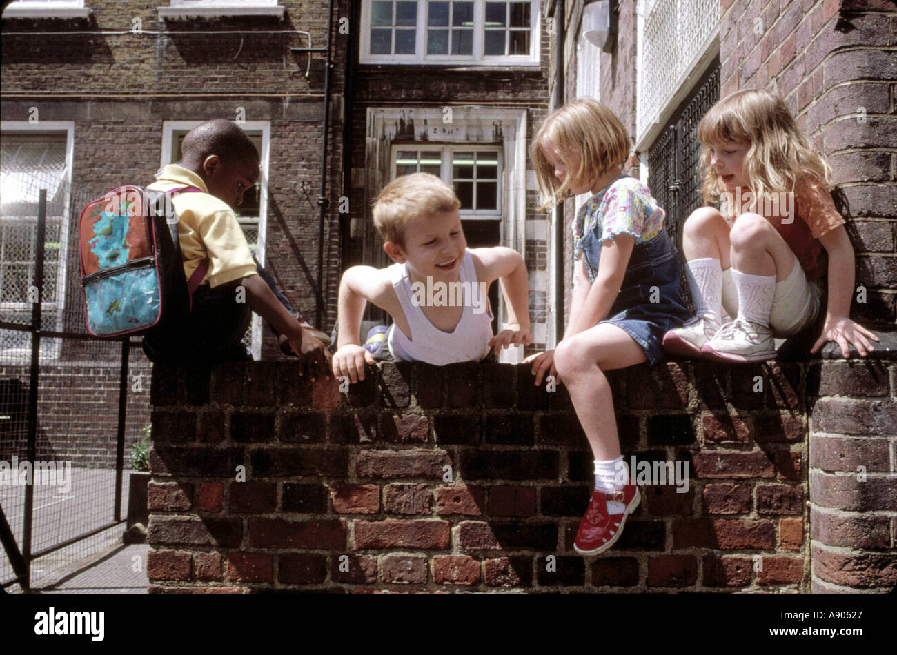 Children playing on playing on wall in school playground Stock Photo ...