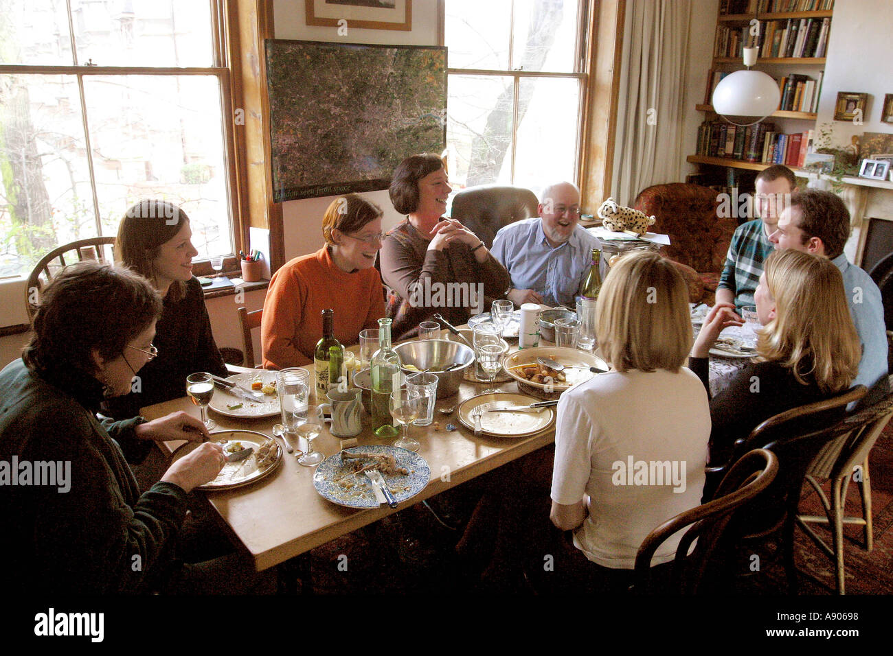 Group of friends sitting around table eating dinner Stock Photo - Alamy