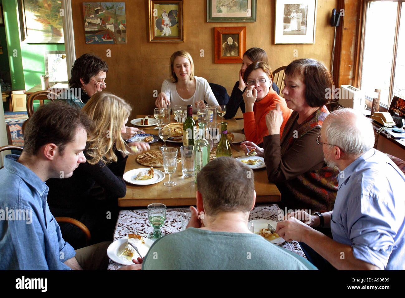 Group of friends sitting around table eating desert Stock Photo - Alamy