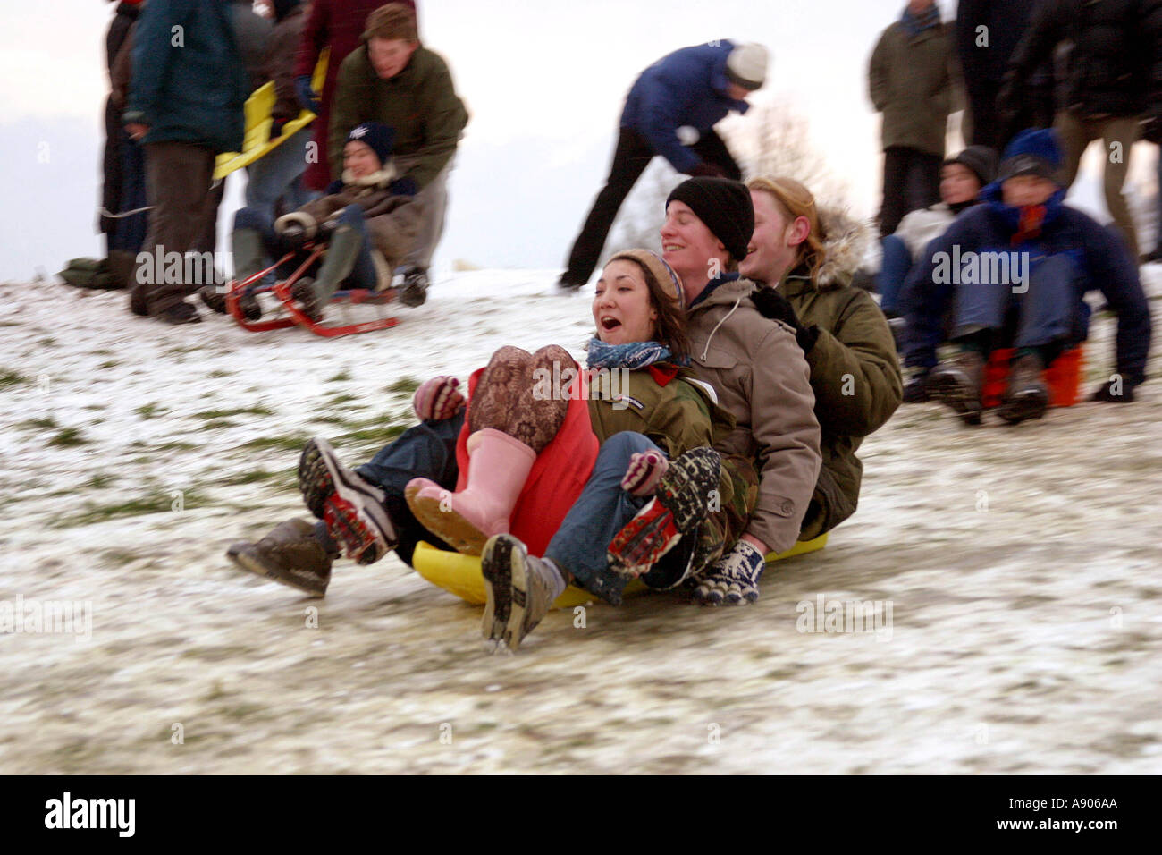 Three friends on a sledge going down a hill Stock Photo - Alamy