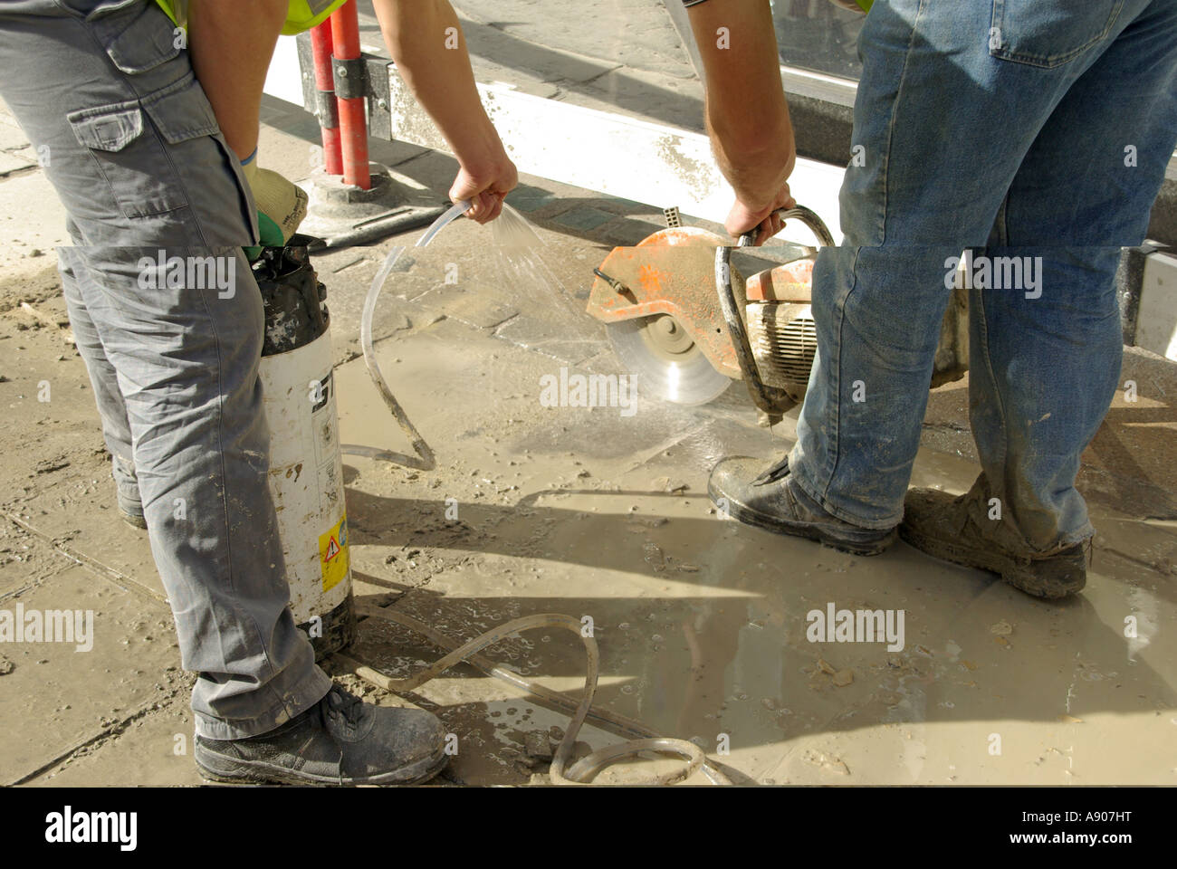 Cracked pavement repairs relaying work in progress two workmen disc ...