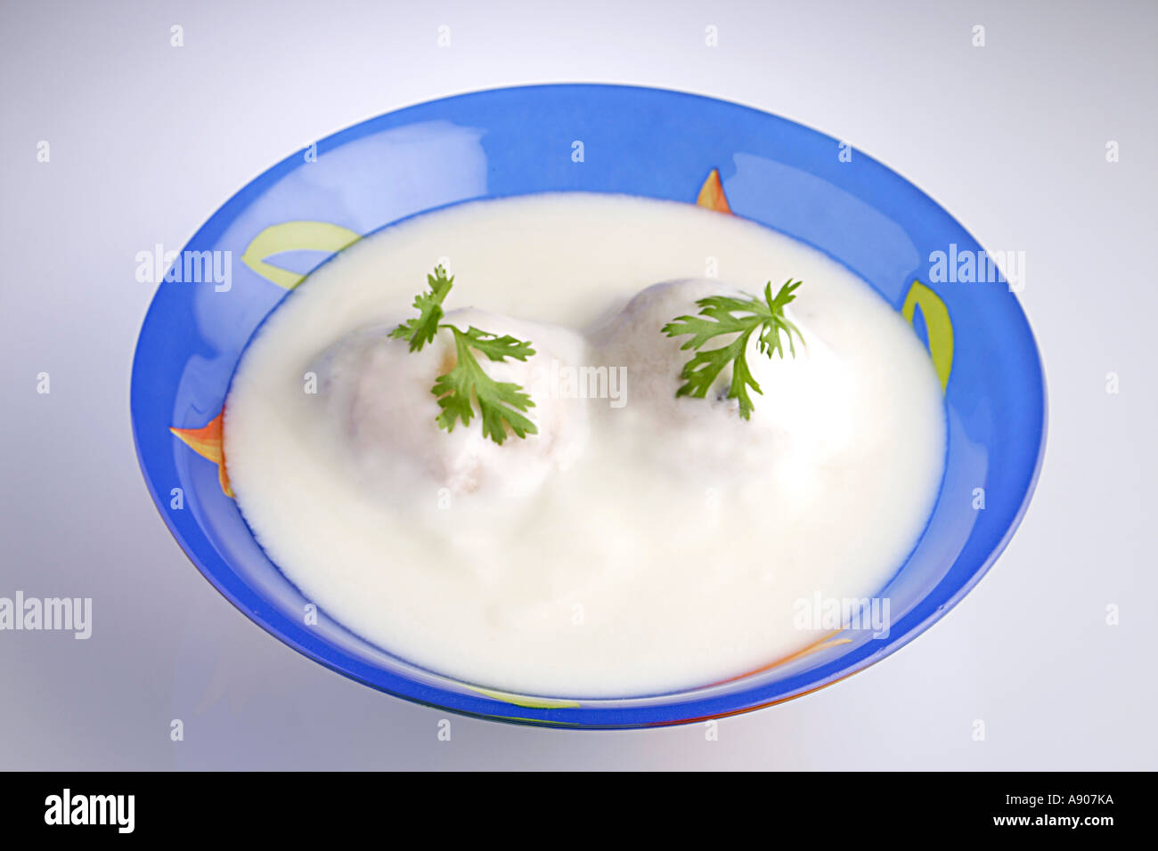 Indian fried dumpling two pieces in curds dahi vada in a blue bowl ...