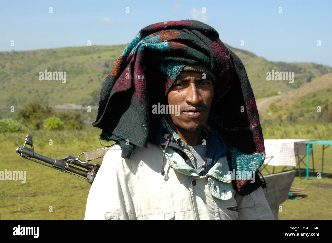 Armed scout with a rifle and a blanket around his hat in Sanakber Camp ...