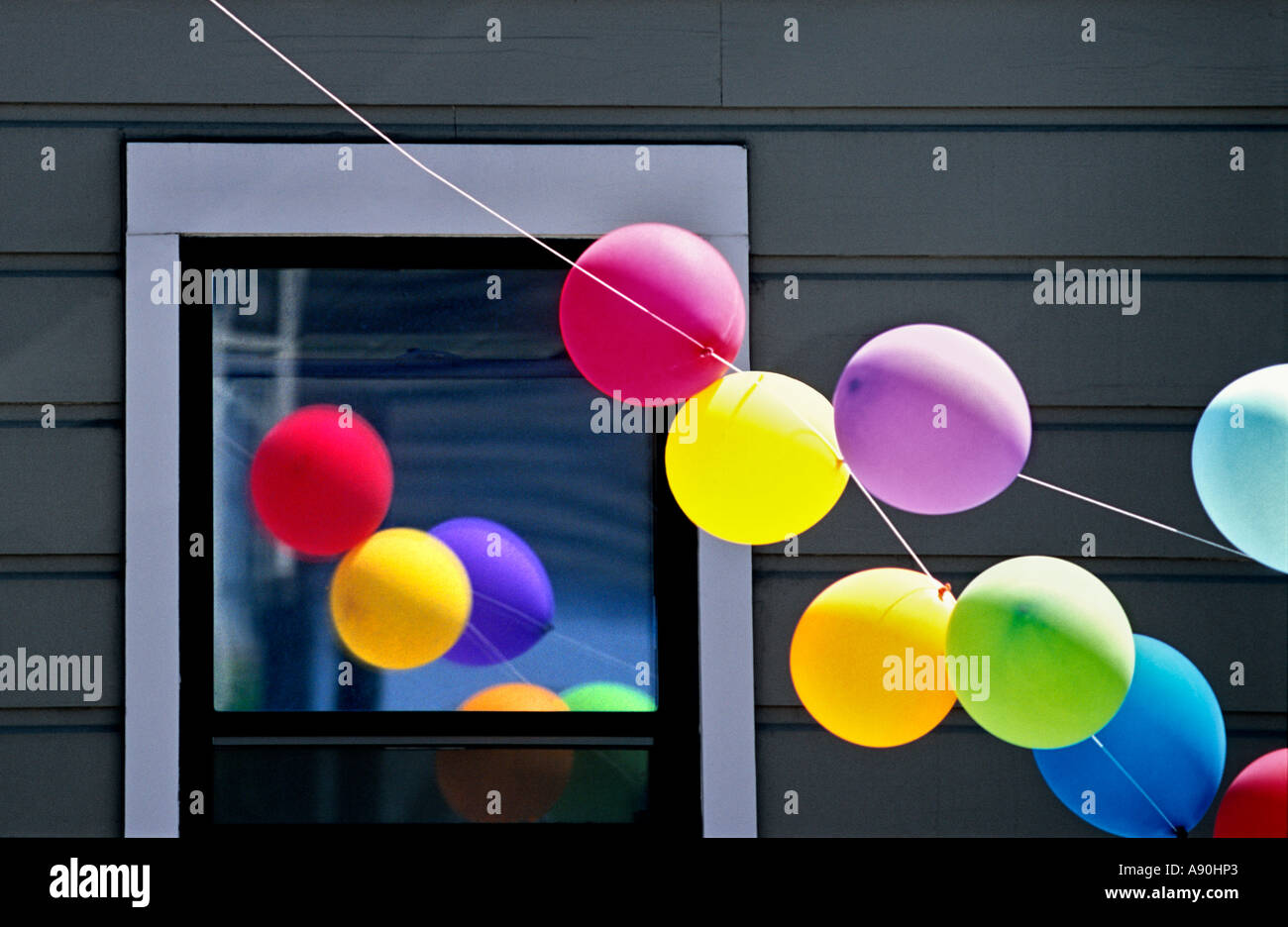 Glass window reflecting image of colored balloons Stock Photo - Alamy