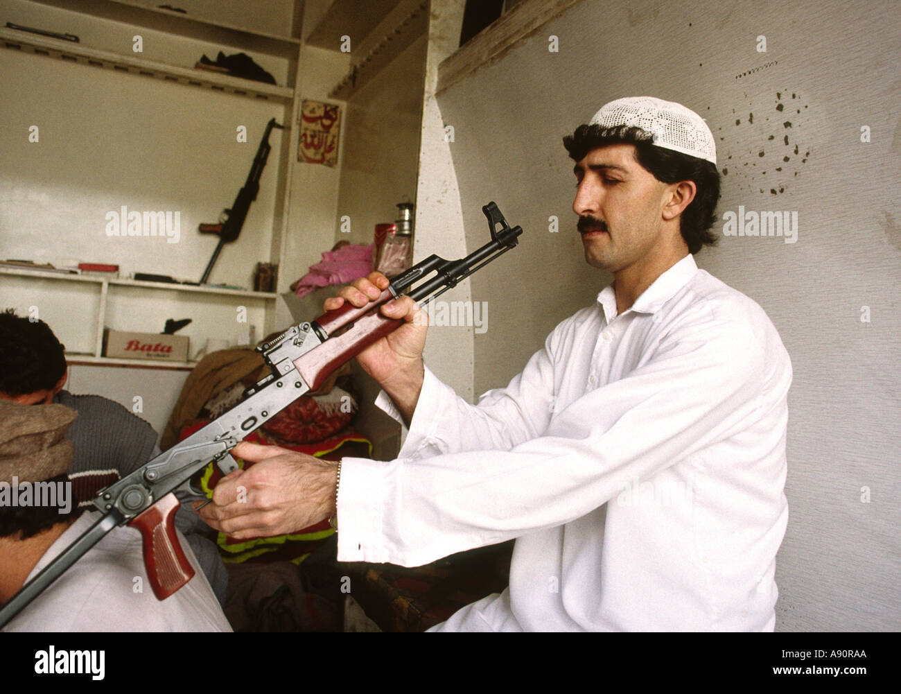 Pakistan NWFP Darra Adam Khel man inspecting copy of AK47 Kalashnikov ...