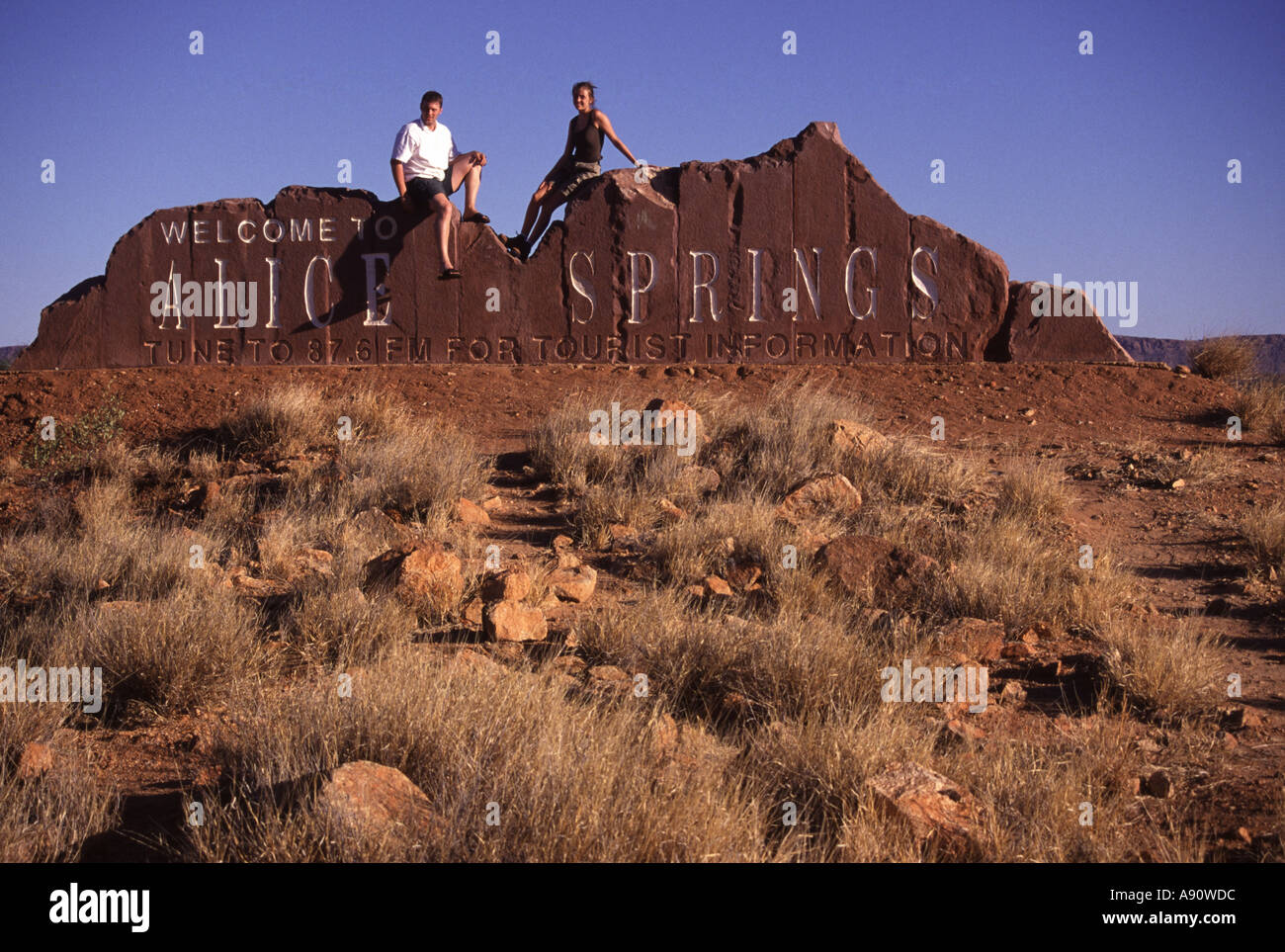 Two adults sitting on Welcome to Alice Springs Rock, Northern Territory ...