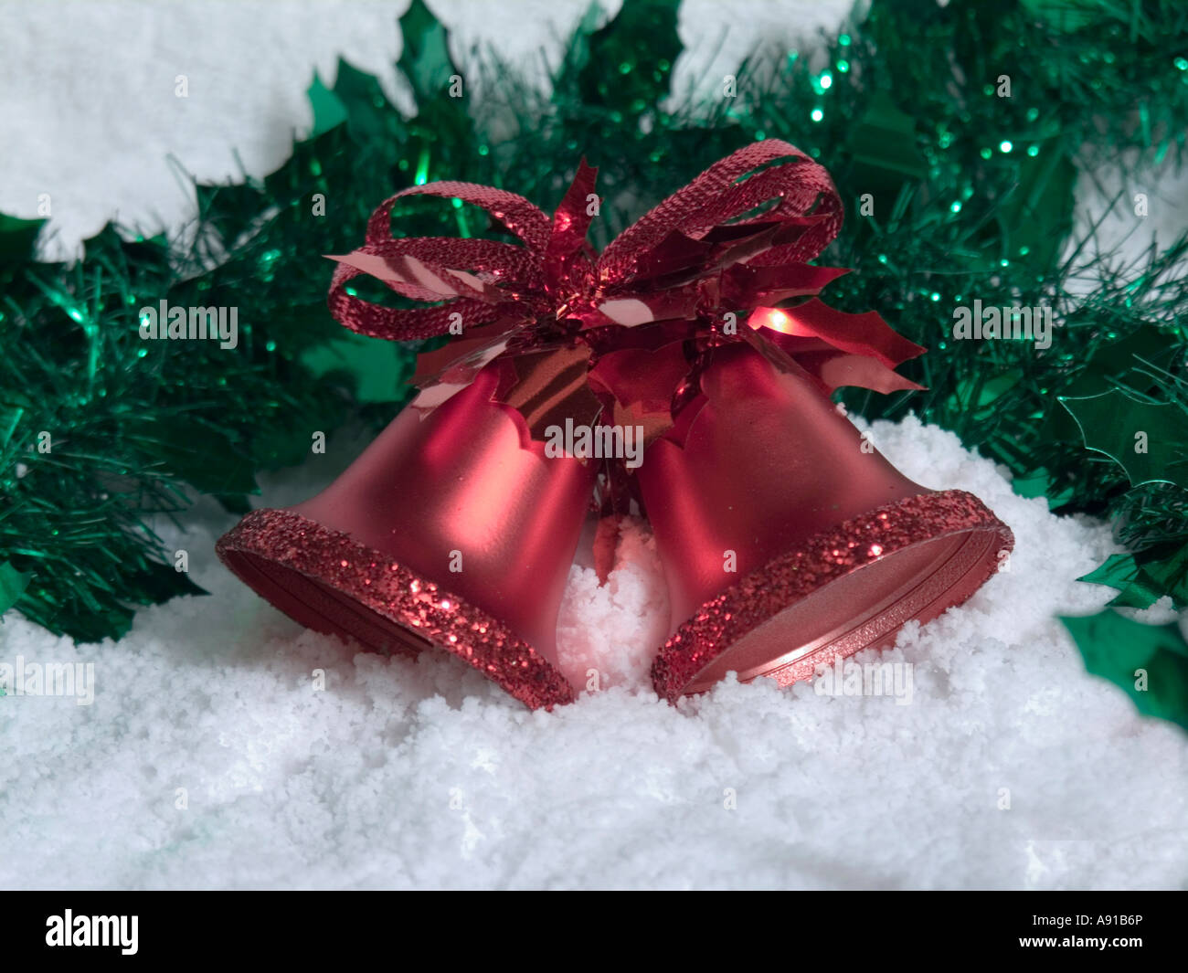 Decorative red bells and green tinsel on snow Stock Photo - Alamy