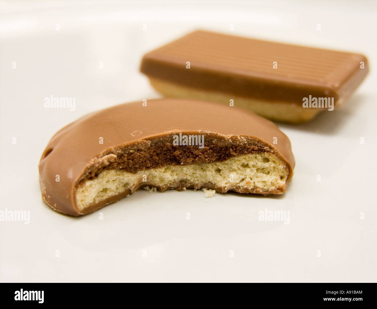 A chocolate biscuit with a bite taken out of it on a white background ...