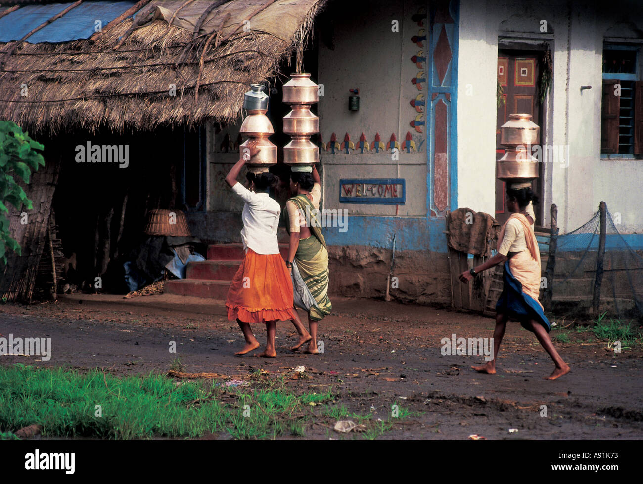 Three Indian woman balancing water in bronze metal pots on their heads ...