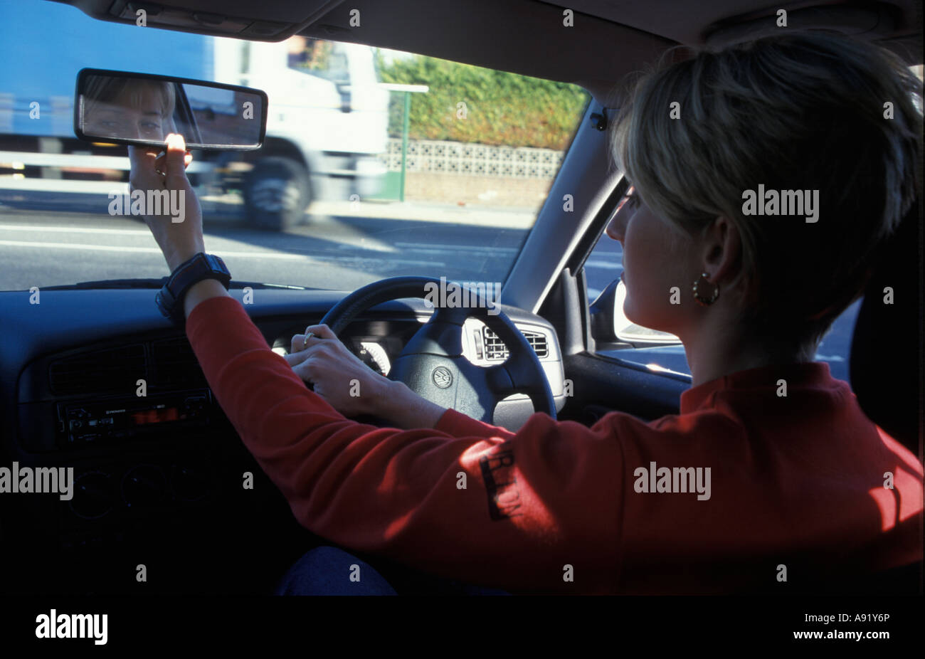female driver adjusting her rear view mirror Stock Photo - Alamy