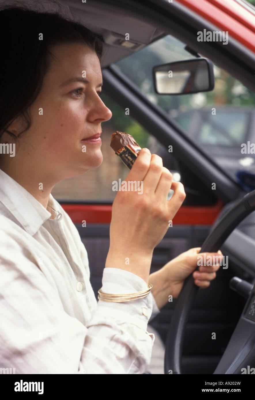 woman driving and eating a chocolate bar Stock Photo - Alamy