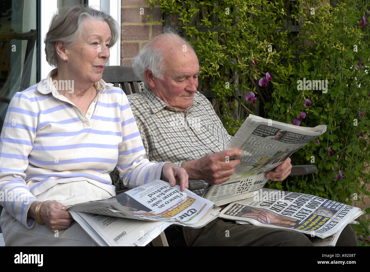 pensioners looking at the newspaper together Stock Photo - Alamy