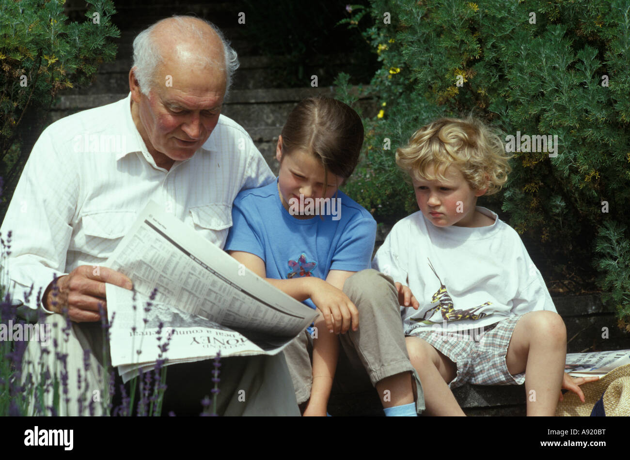 grandfather reading the newspaper with his grandchildren Stock Photo ...