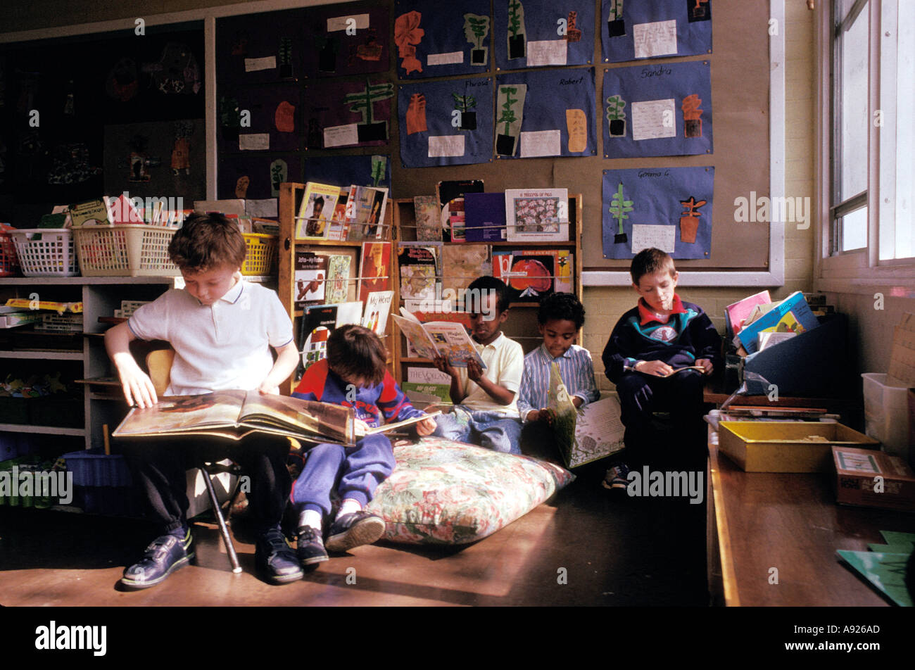 A group of children quietly reading in the book corner of the classroom ...