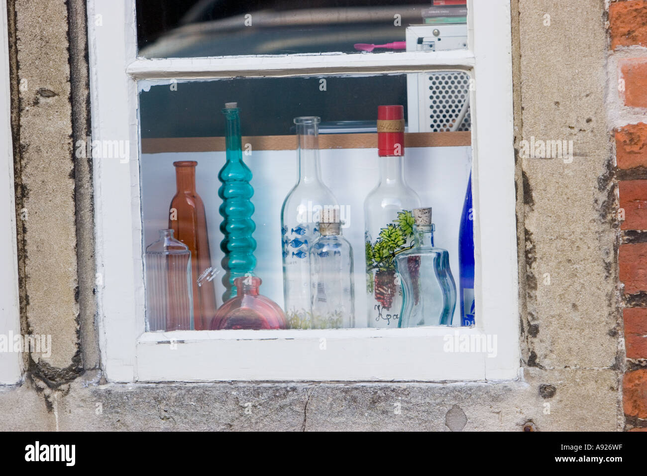 Different shaped and coloured glass bottles displayed in a window Stock ...