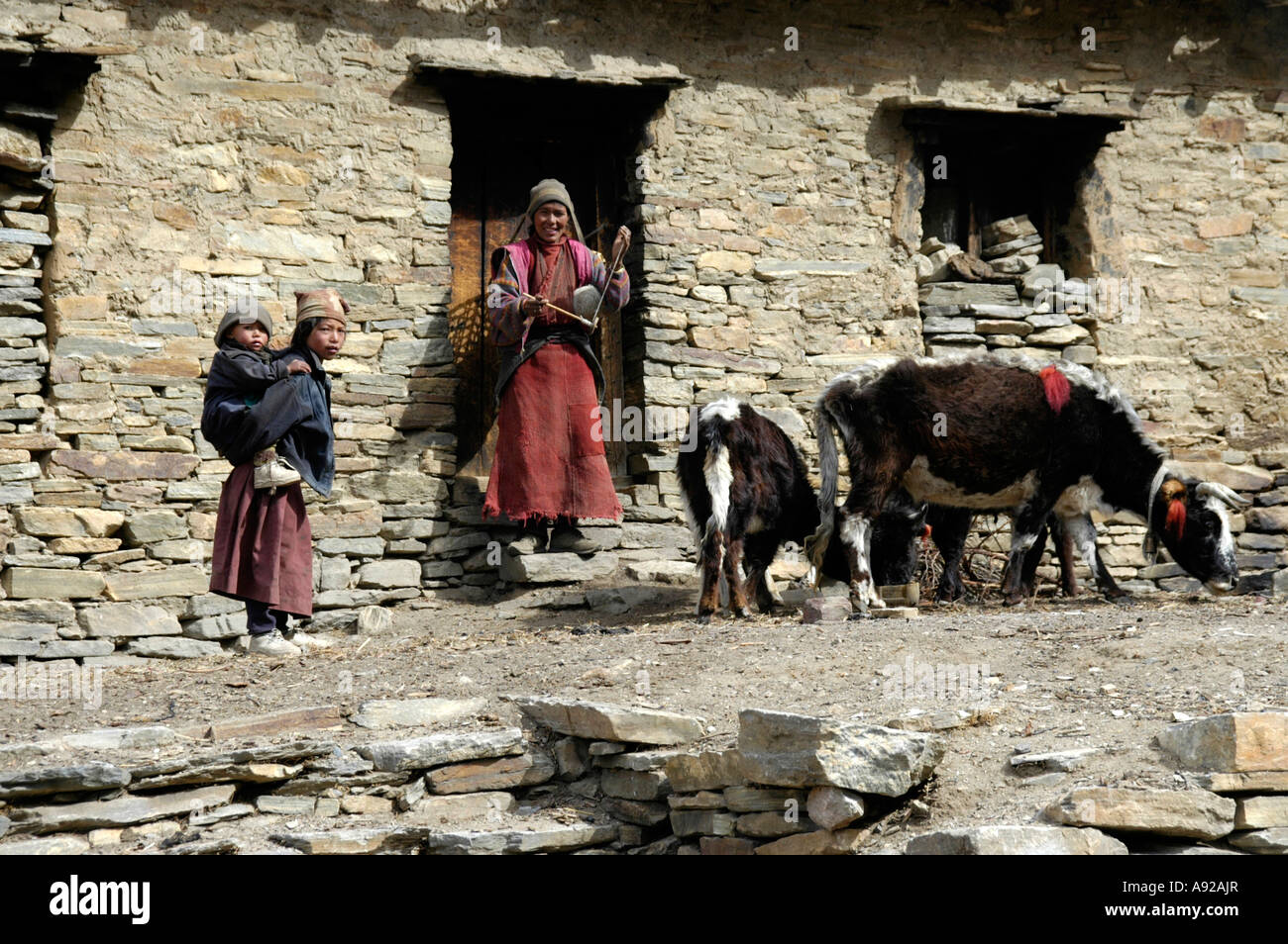 Woman girl and baby in traditional cloth at a stone built house Chyakhu ...