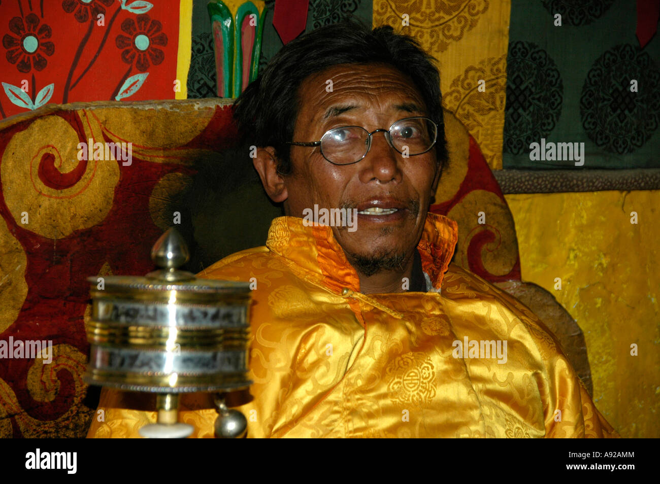 Portrait monk Lama Sonom dressed in a yellow cape wearing glasses ...
