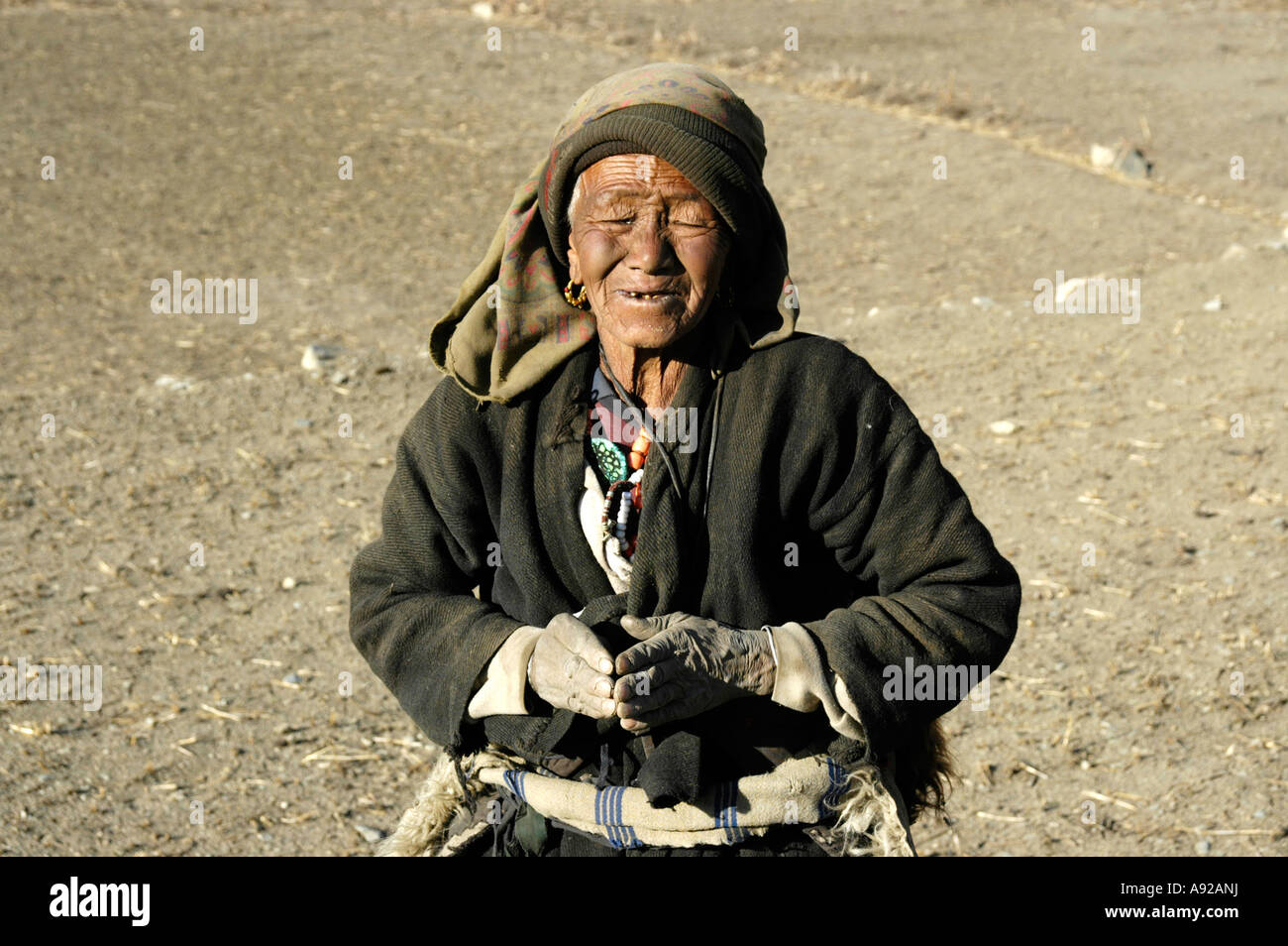 Old Tibetan woman is folding her hands for prayer on the field Nar Nar ...