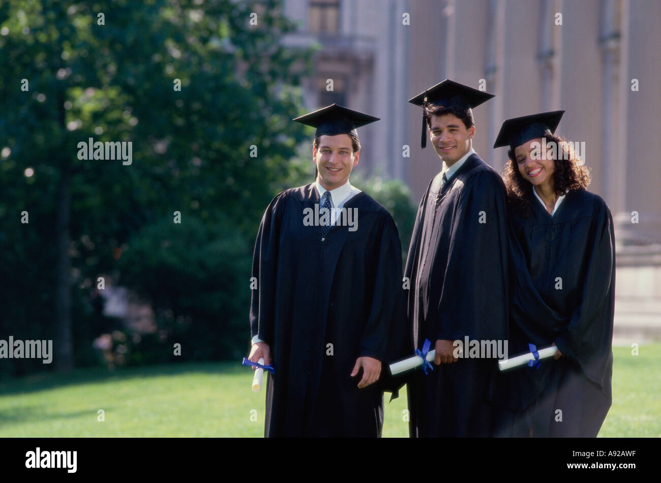 Two male graduates with a female graduate holding diplomas Stock Photo ...