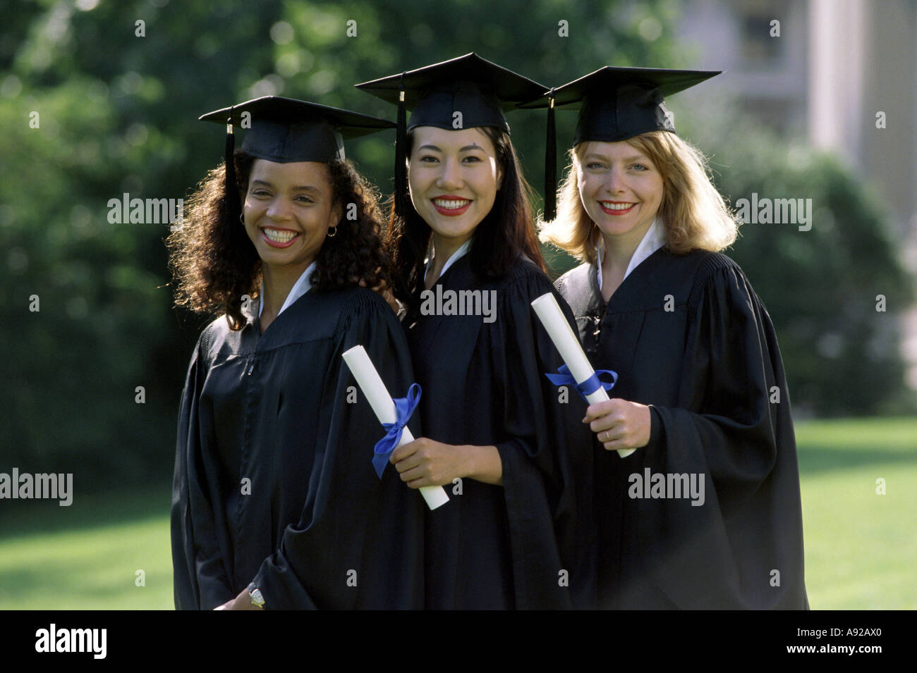 Three young women wearing graduation gowns and holding diplomas Stock ...