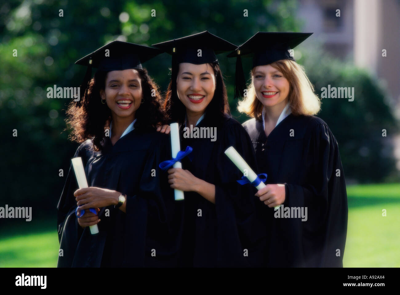 Three young women wearing graduation gowns and holding diplomas Stock ...