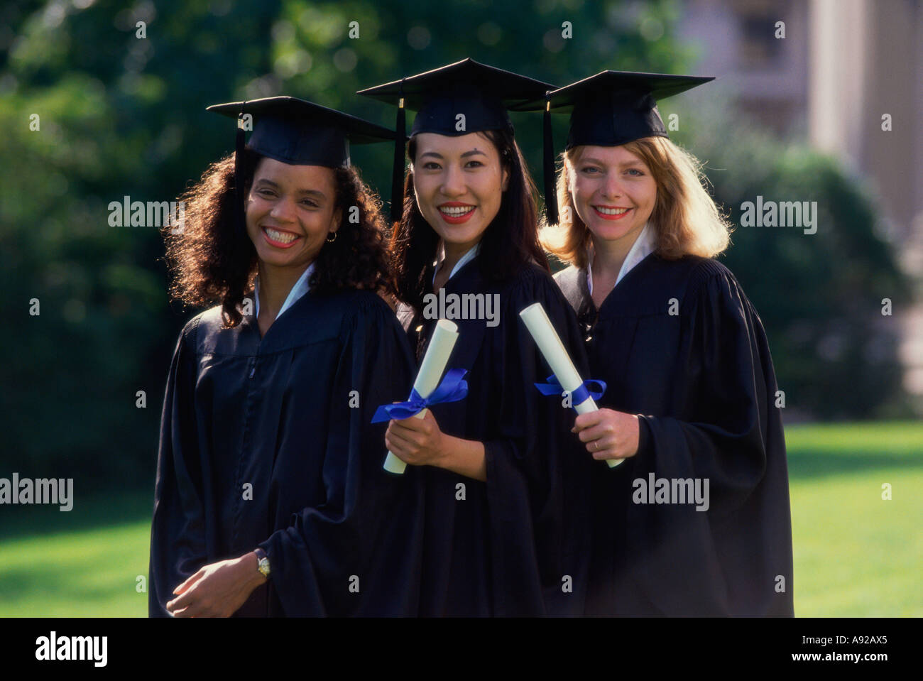 Three young women wearing graduation gowns and holding diplomas Stock ...