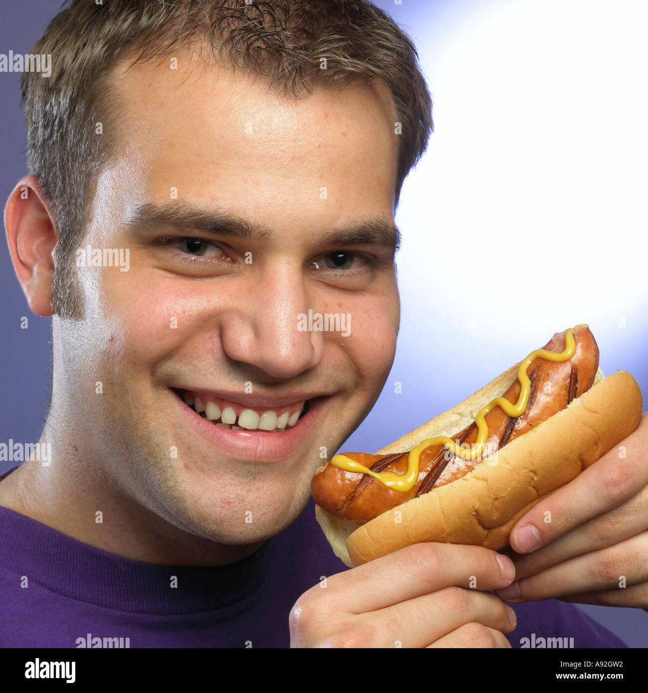 Portrait of a young man holding a hot dog Stock Photo - Alamy