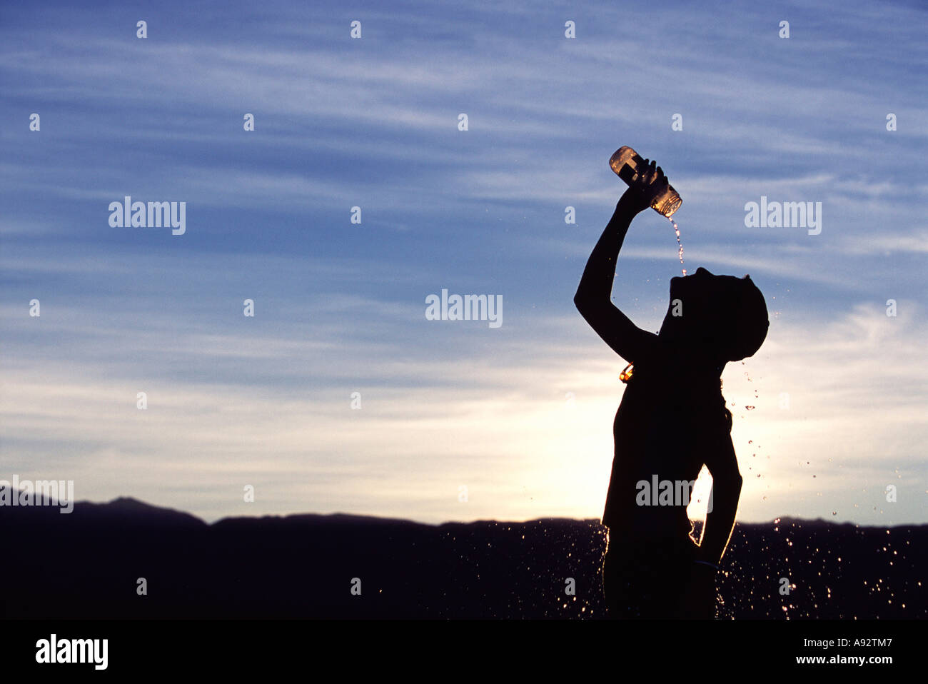 Silhouette of a man drinking water at dusk Stock Photo - Alamy