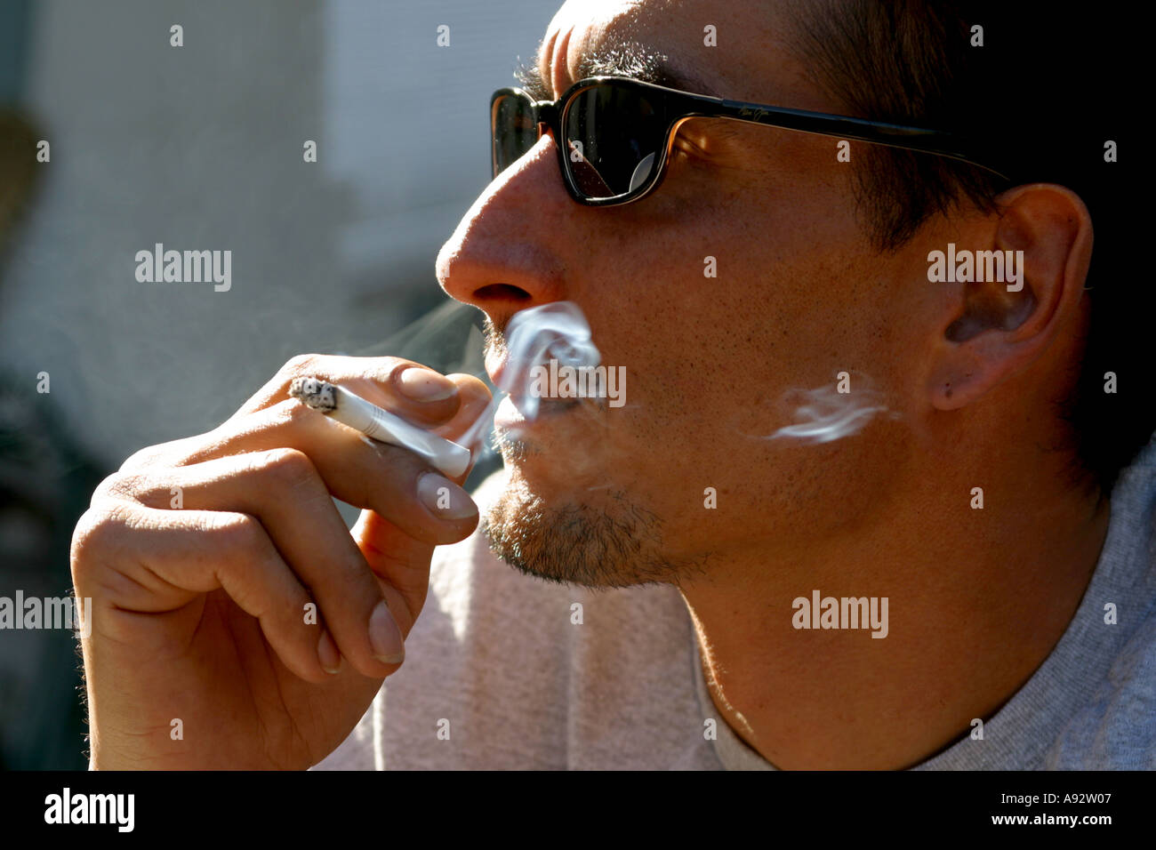 A young man is smoking a cigarette in the sunshine Stock Photo - Alamy