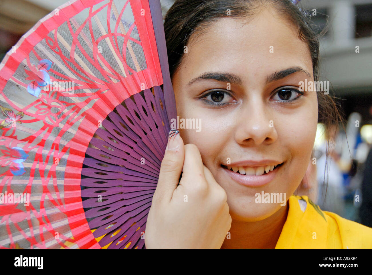 Beautiful young woman with fan next to her face Stock Photo - Alamy