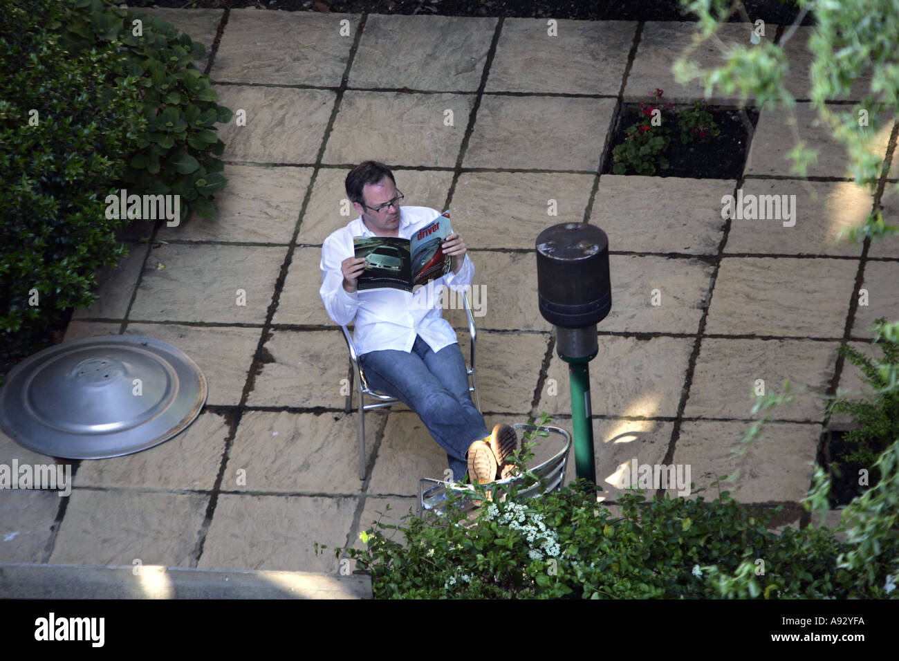 Man reading magazine in his back garden, London Stock Photo - Alamy