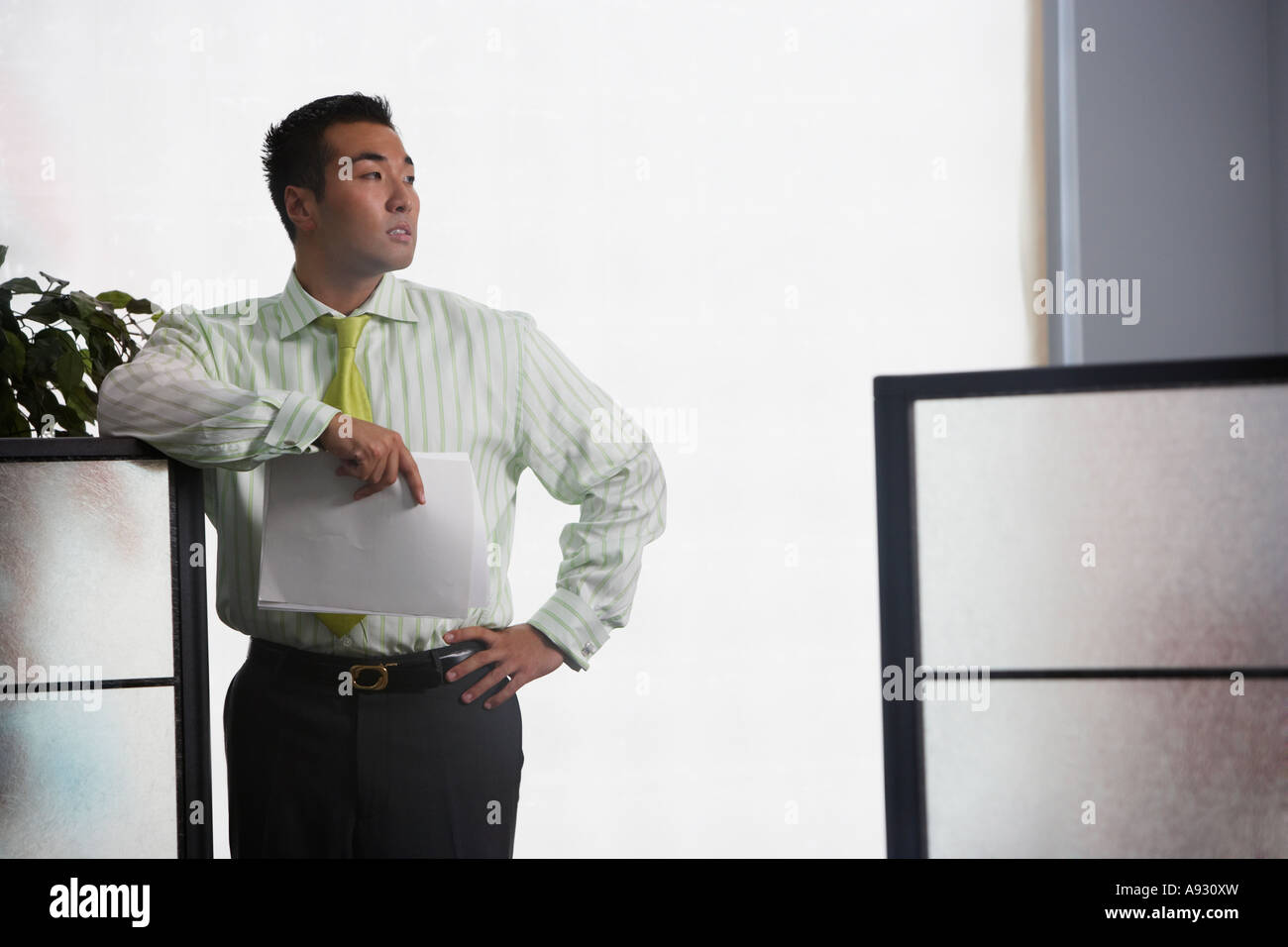Asian businessman leaning on cubicle wall Stock Photo - Alamy