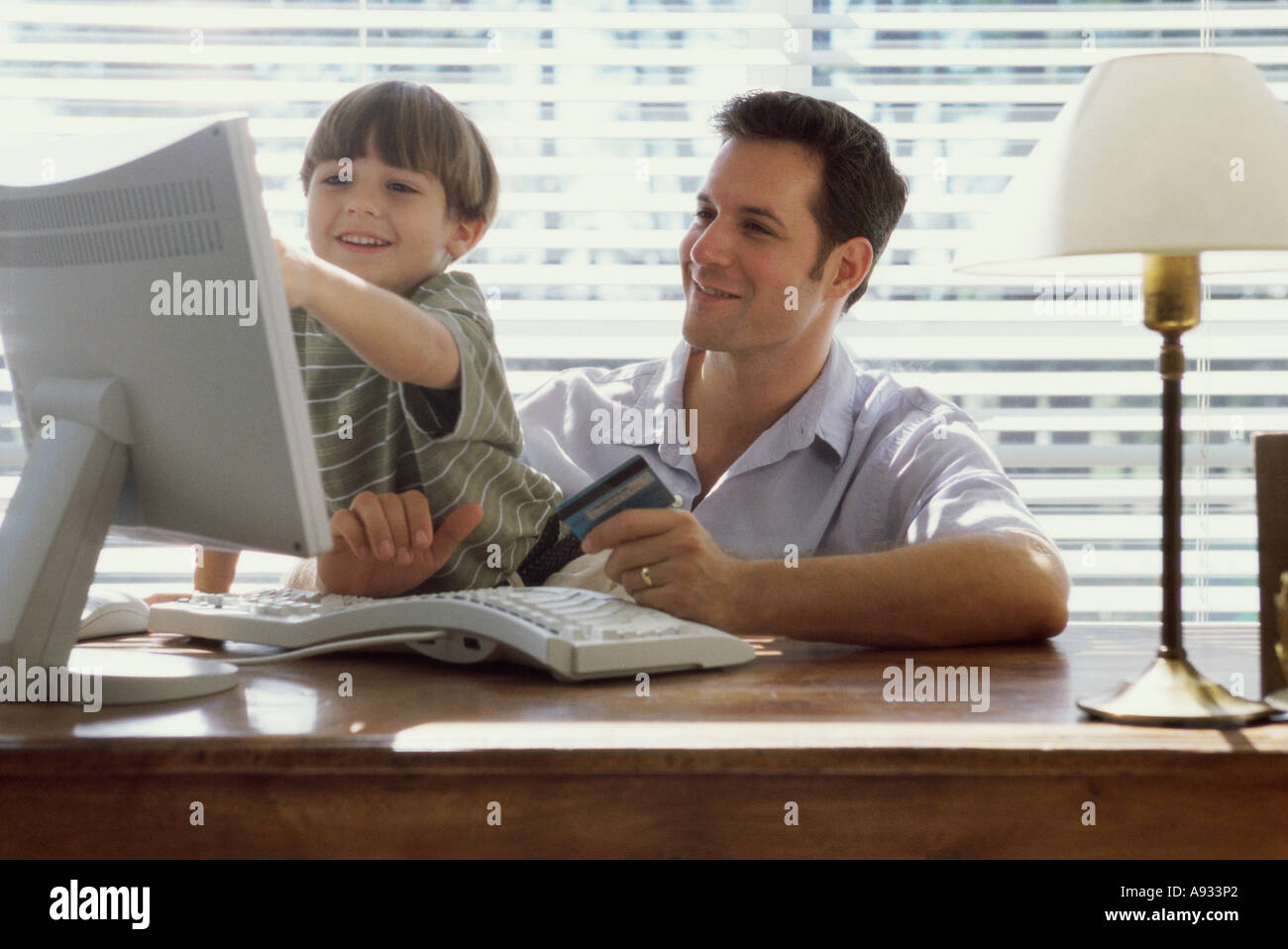 Father and son sitting in front of a computer Stock Photo - Alamy