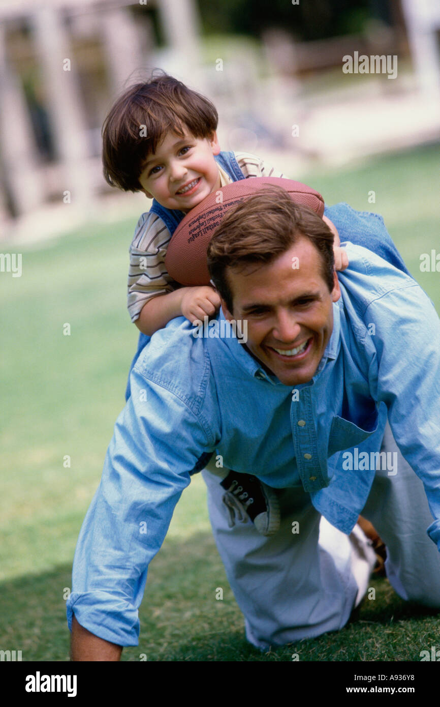Son riding on his father's back Stock Photo - Alamy